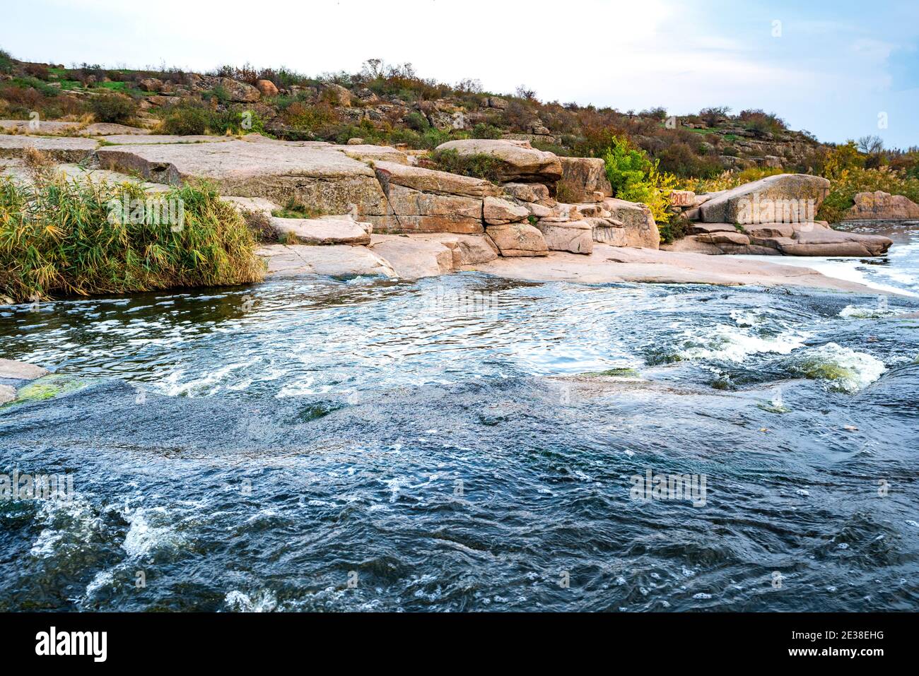A small shining stream flows among smooth wet and dark stones and dry ...