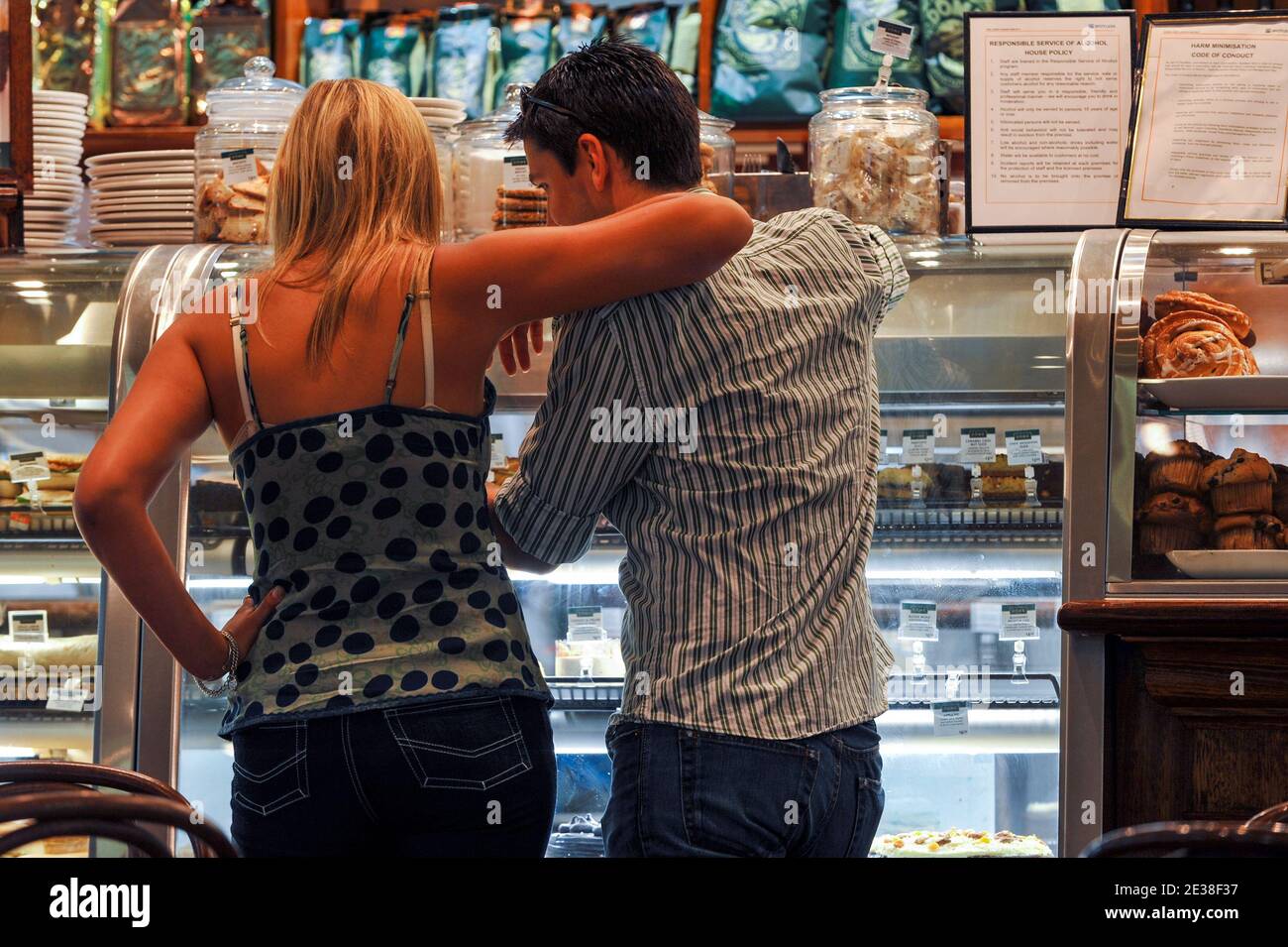 A rear view image of a young couple at a cafe looking at dining options ...