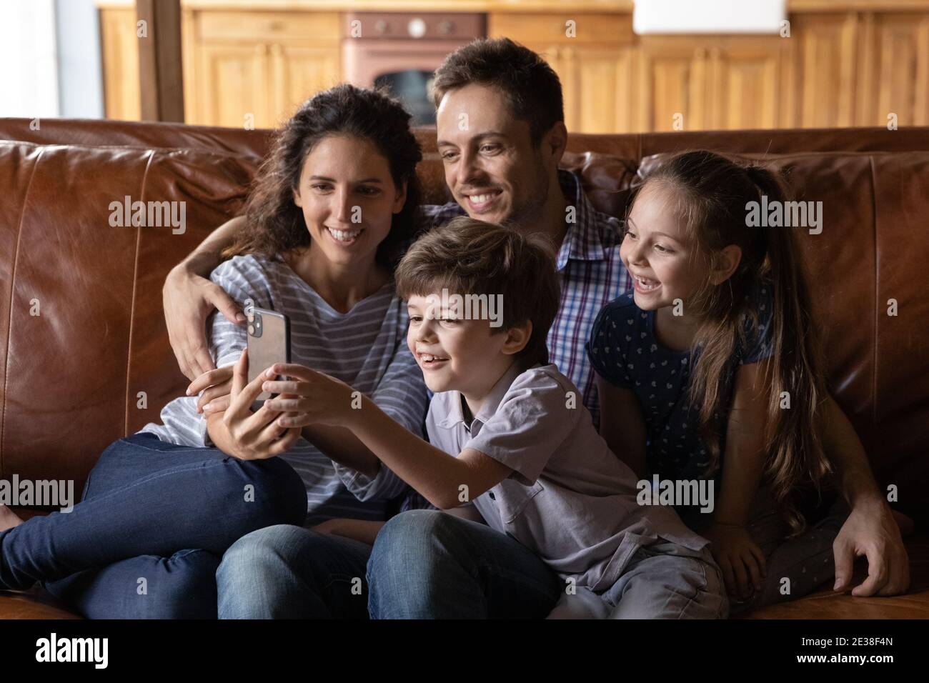 Happy parents have fun using cellphone with kids Stock Photo - Alamy