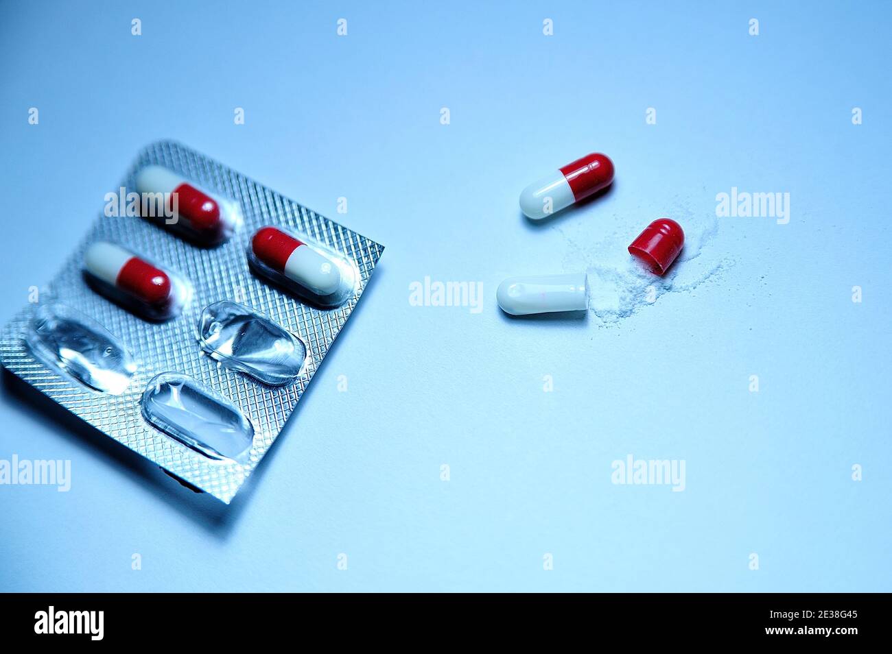 Medical capsules, one of them opened on white surface Stock Photo - Alamy