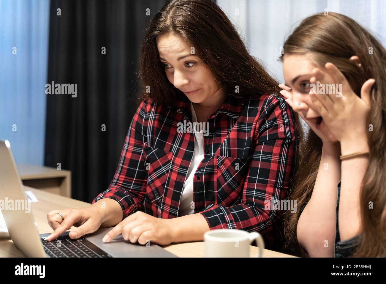 Two young girls or woman looks at laptop at home with funny surprise ...
