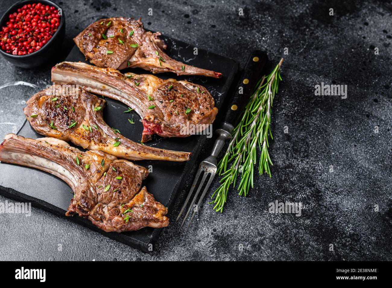 Barbecue fried lamb meat chops on a marble board. Black background. Top ...