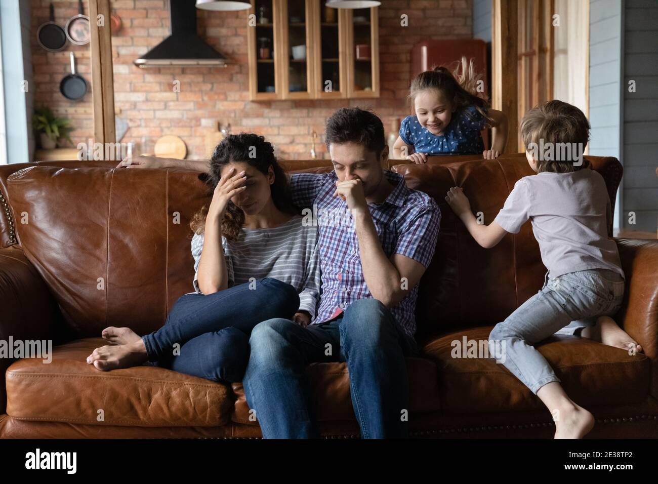 Tired parents distressed by naughty small children Stock Photo - Alamy