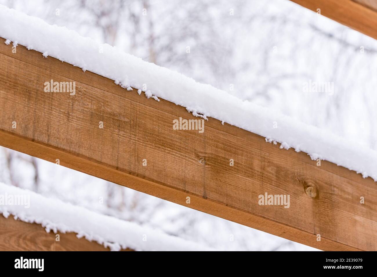Wooden beam covered with snow. Wood construction outside after snowfall ...