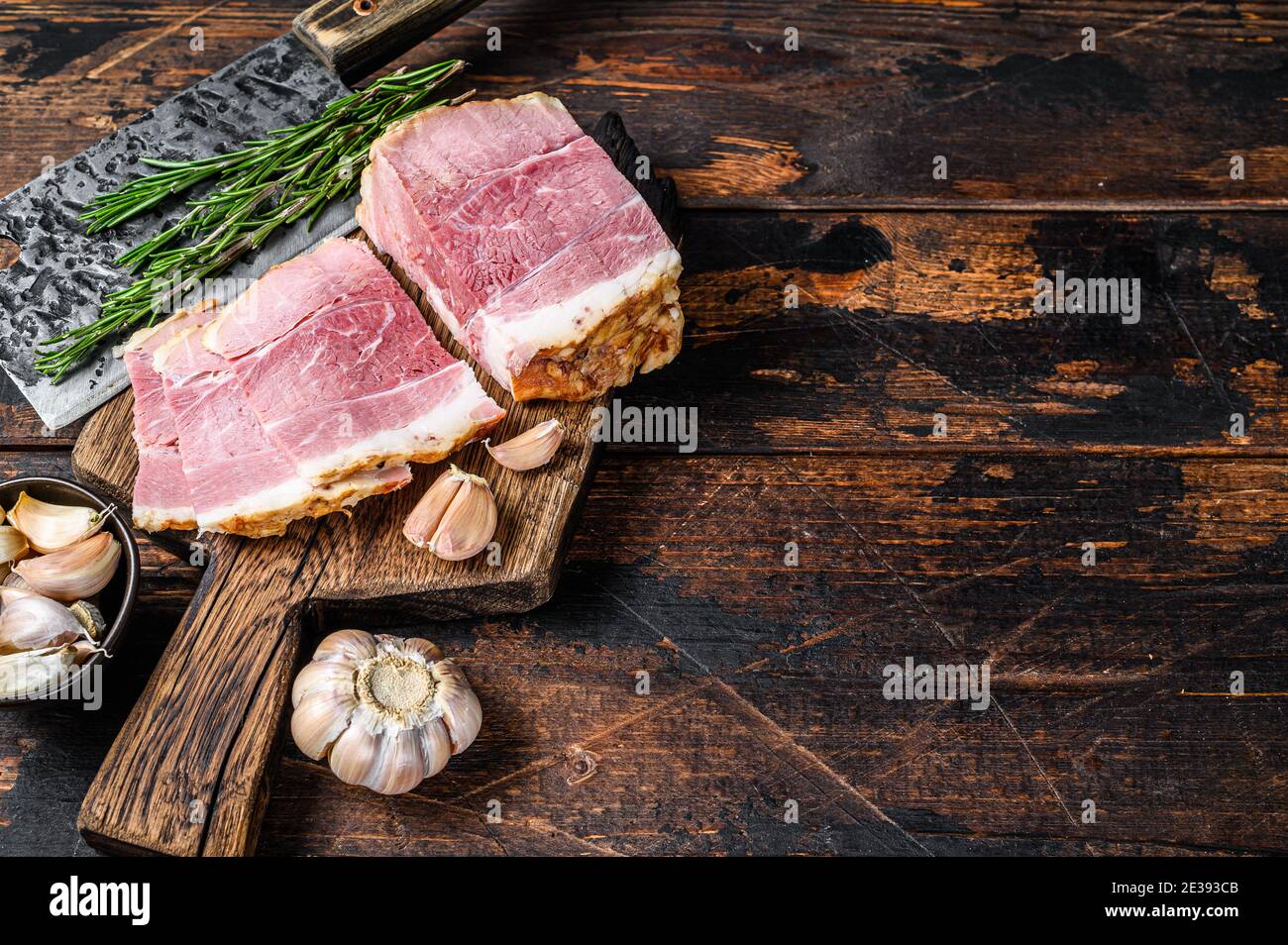 Smoked pork gammon meat slices on a wooden rustic cutting board. Dark ...