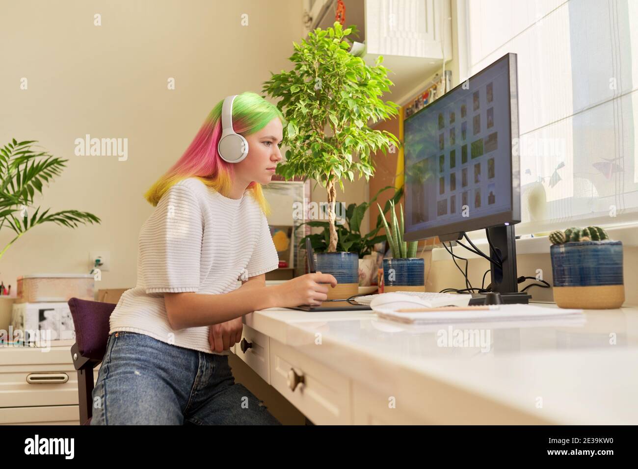 Girl teenager artist in headphones drawing on computer using graphics ...