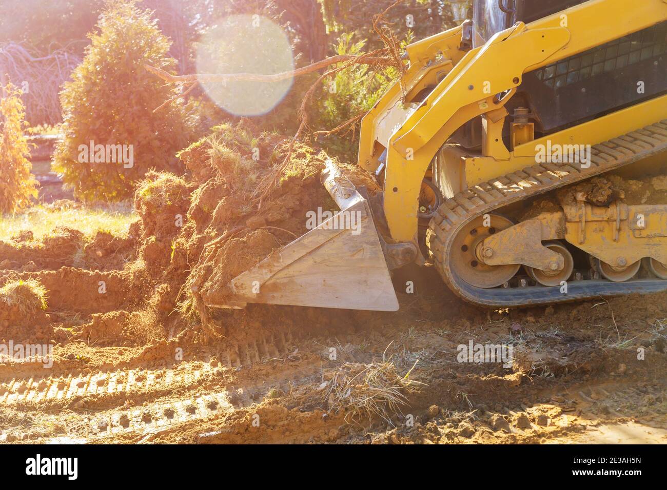 Mini bulldozer working with earth while doing landscaping works on ...