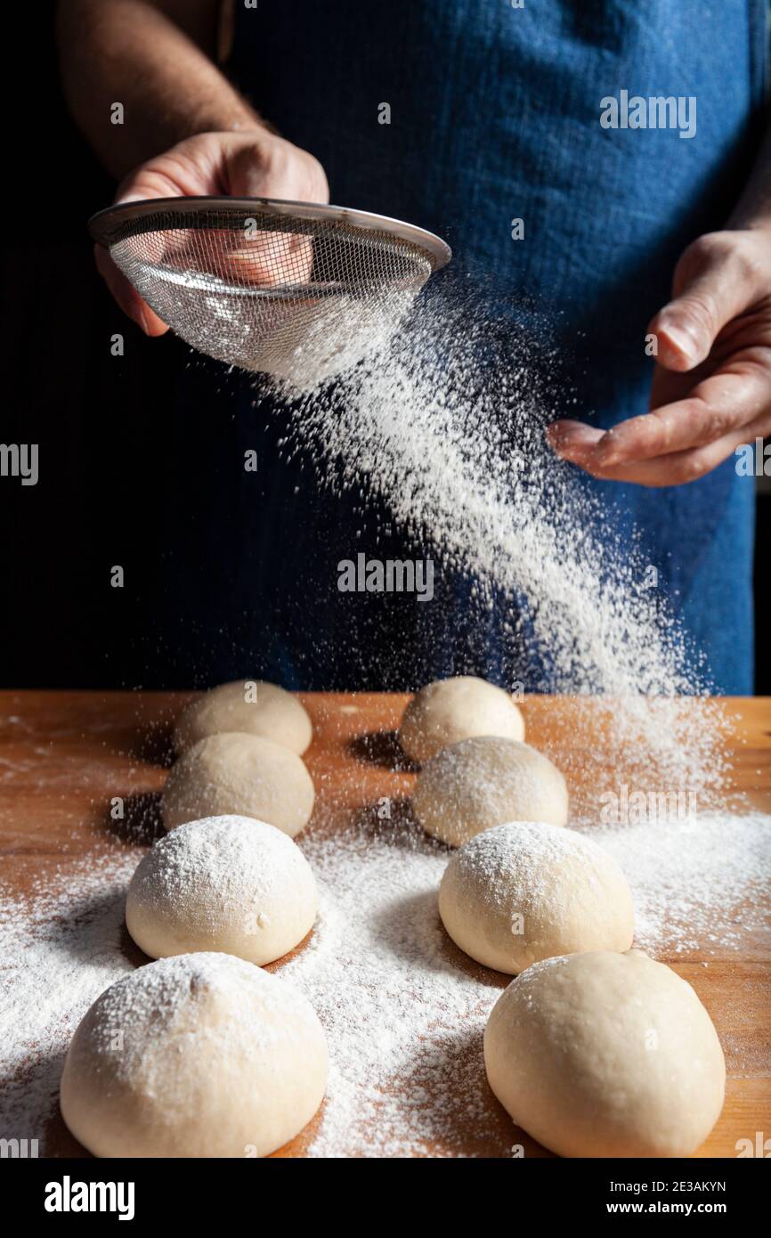 Baker's hands sprinkle dough with flour using a sieve Stock Photo - Alamy