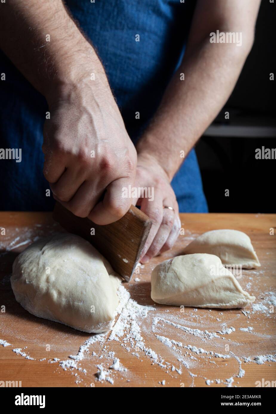 Baker hands cutting off piece of dough with old dough scrapper over ...