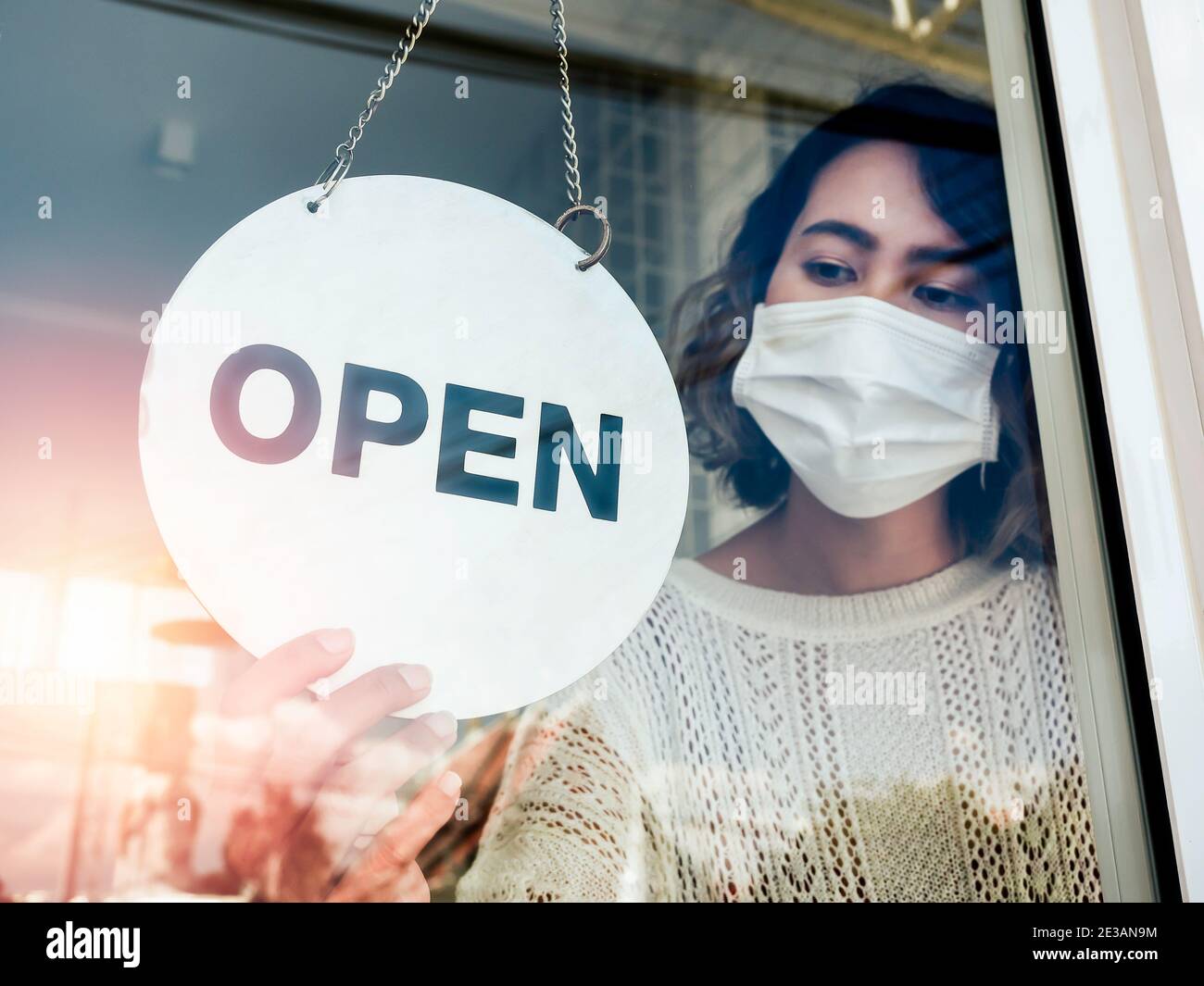 Open sign hanging on the glass door, soft focus. Woman hand flip OPEN ...