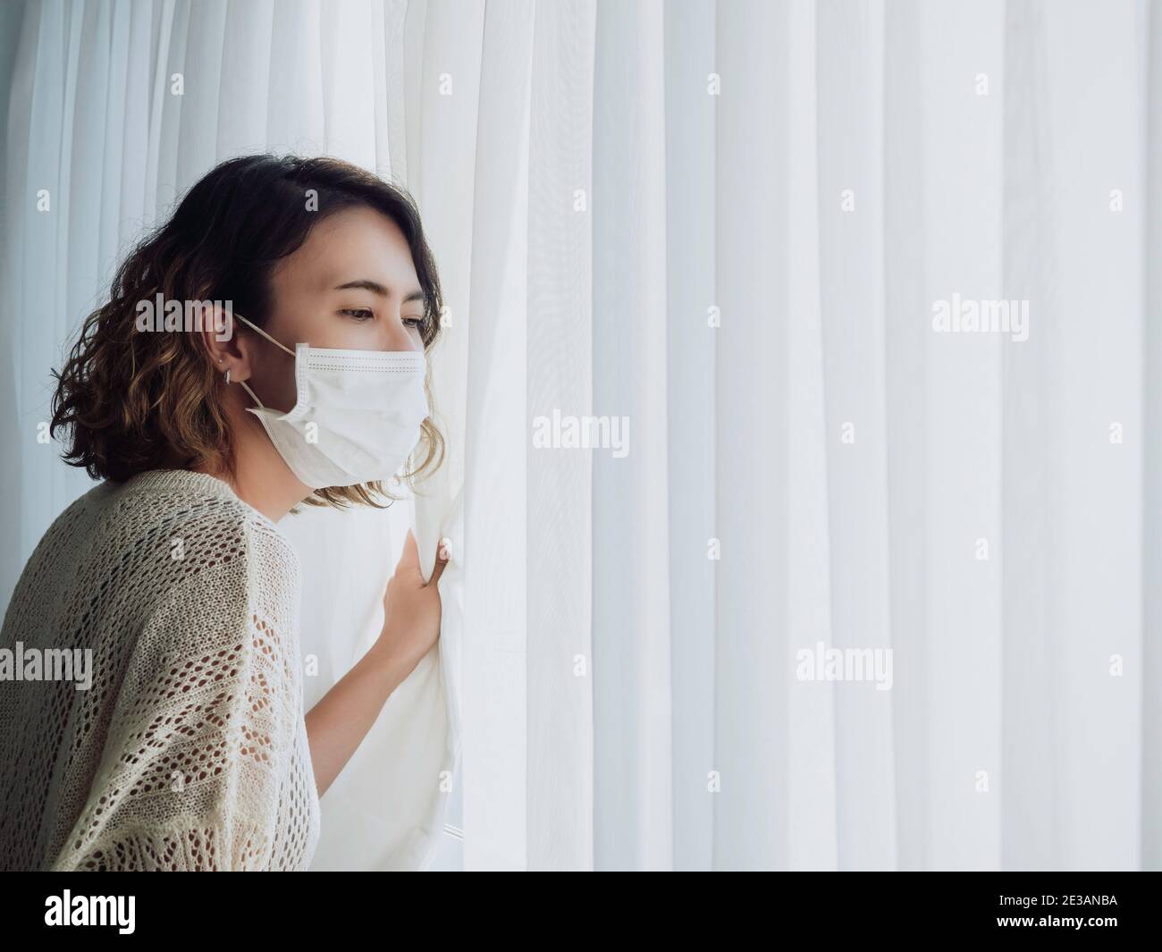 Beautiful lonely Asian woman wearing medical face mask looking out the ...
