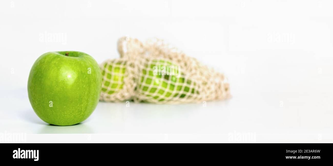 Green apples in eco mesh bag on white kitchen table. Market shopping ...