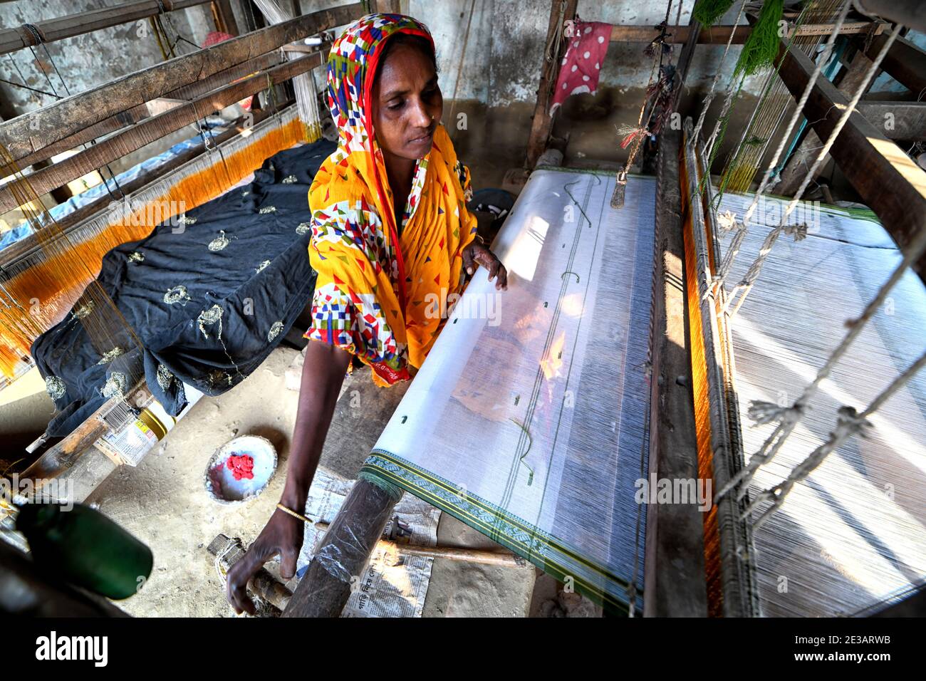 A female worker seen working on a handloom machine to produce fibres ...
