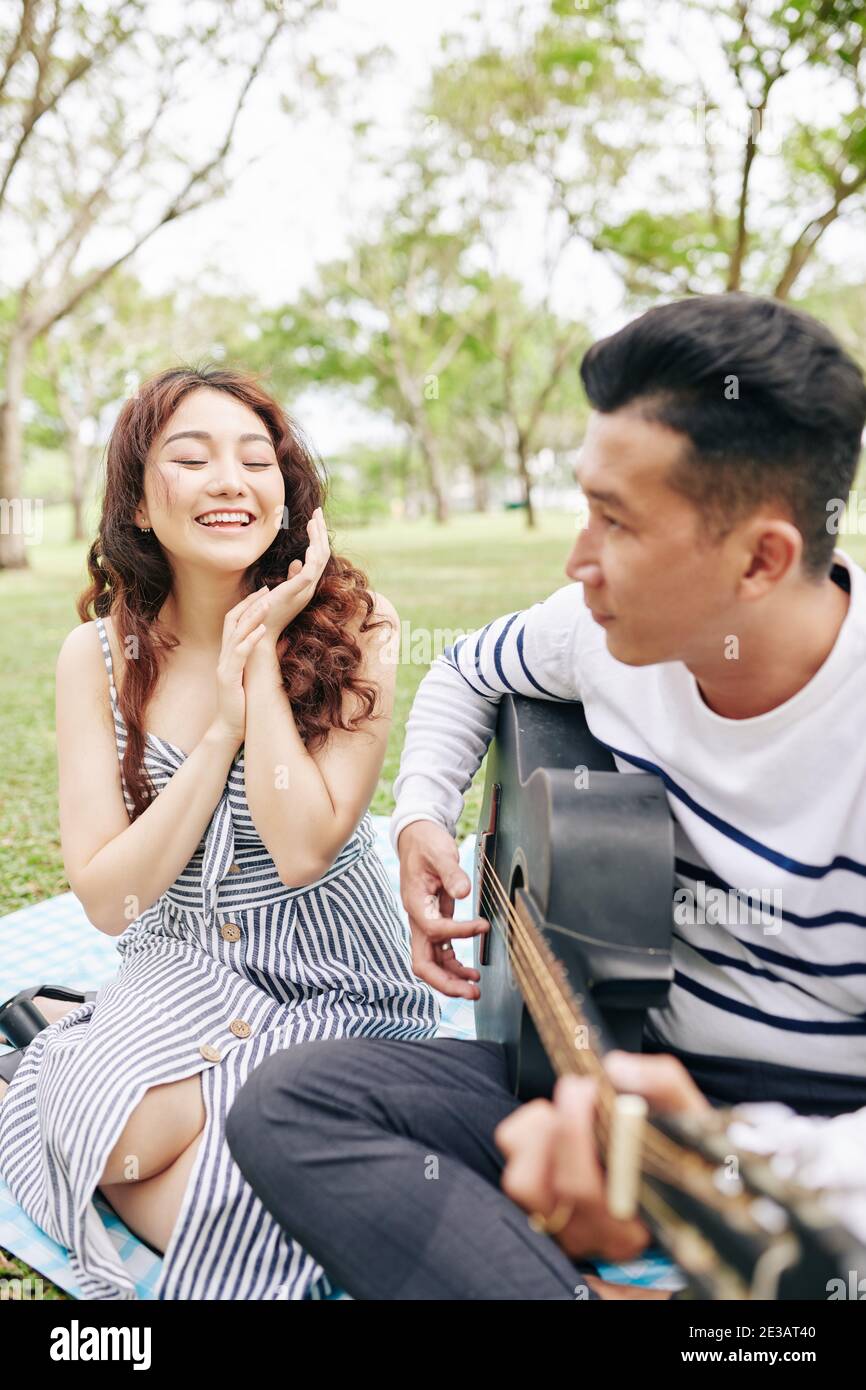 Happy excited young woman applauding her boyfriend singing and playing ...