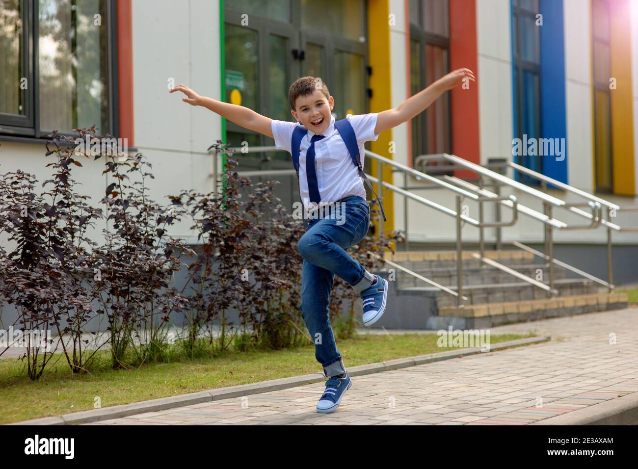 Cheerful fun young schoolboy jumping against school Stock Photo - Alamy