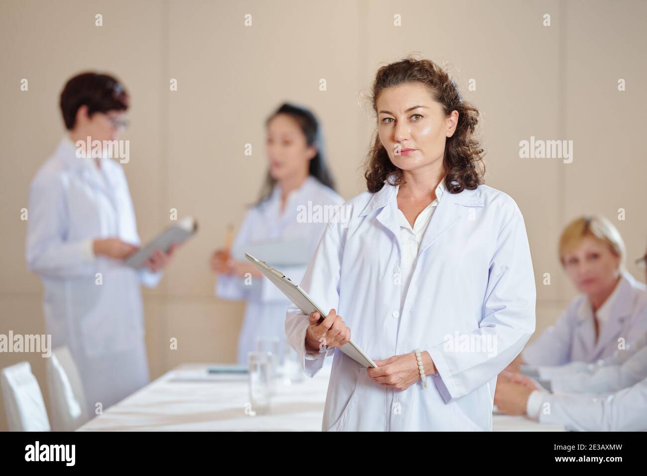 Portrait of serious mature female researcher holding clipboard and ...