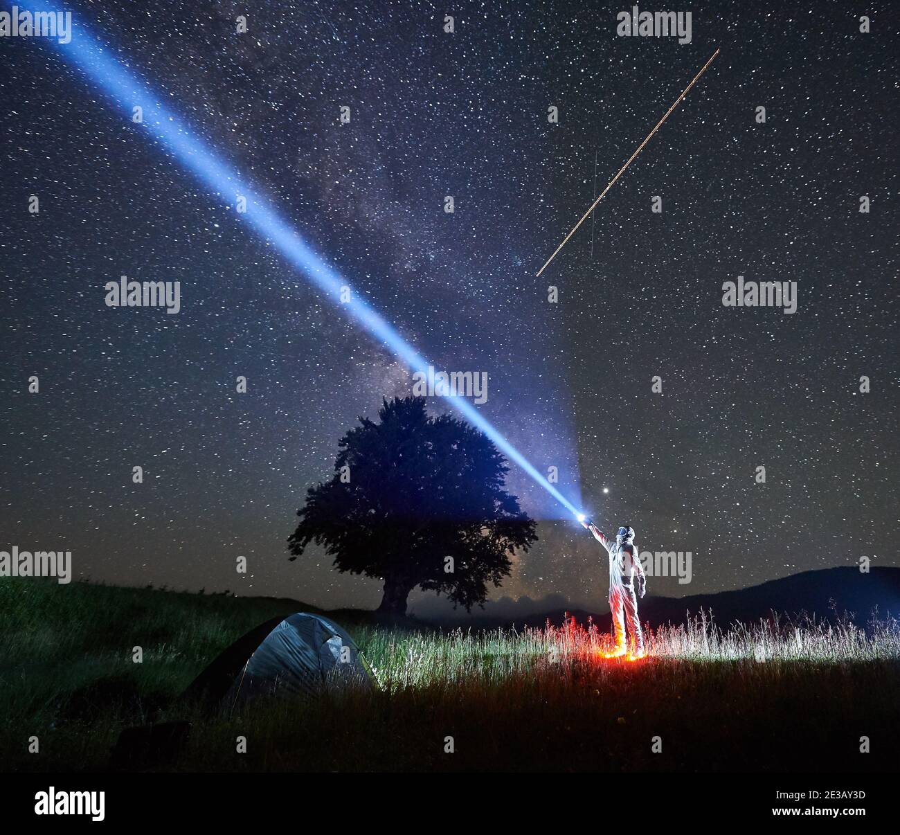 Illuminated spaceman in space suit and helmet directs a ray of light ...