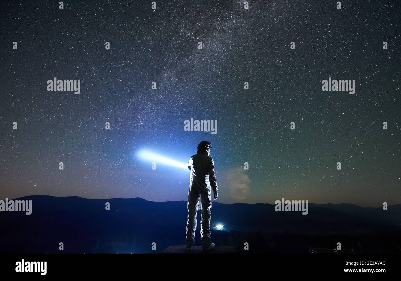 Cosmonaut wearing white space suit and helmet directs a blue ray of ...