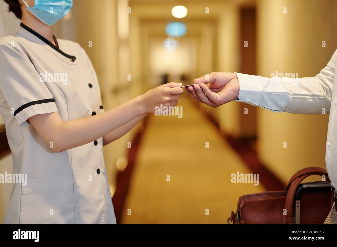 Close-up image of hotel manager in protective mask giving electronic ...