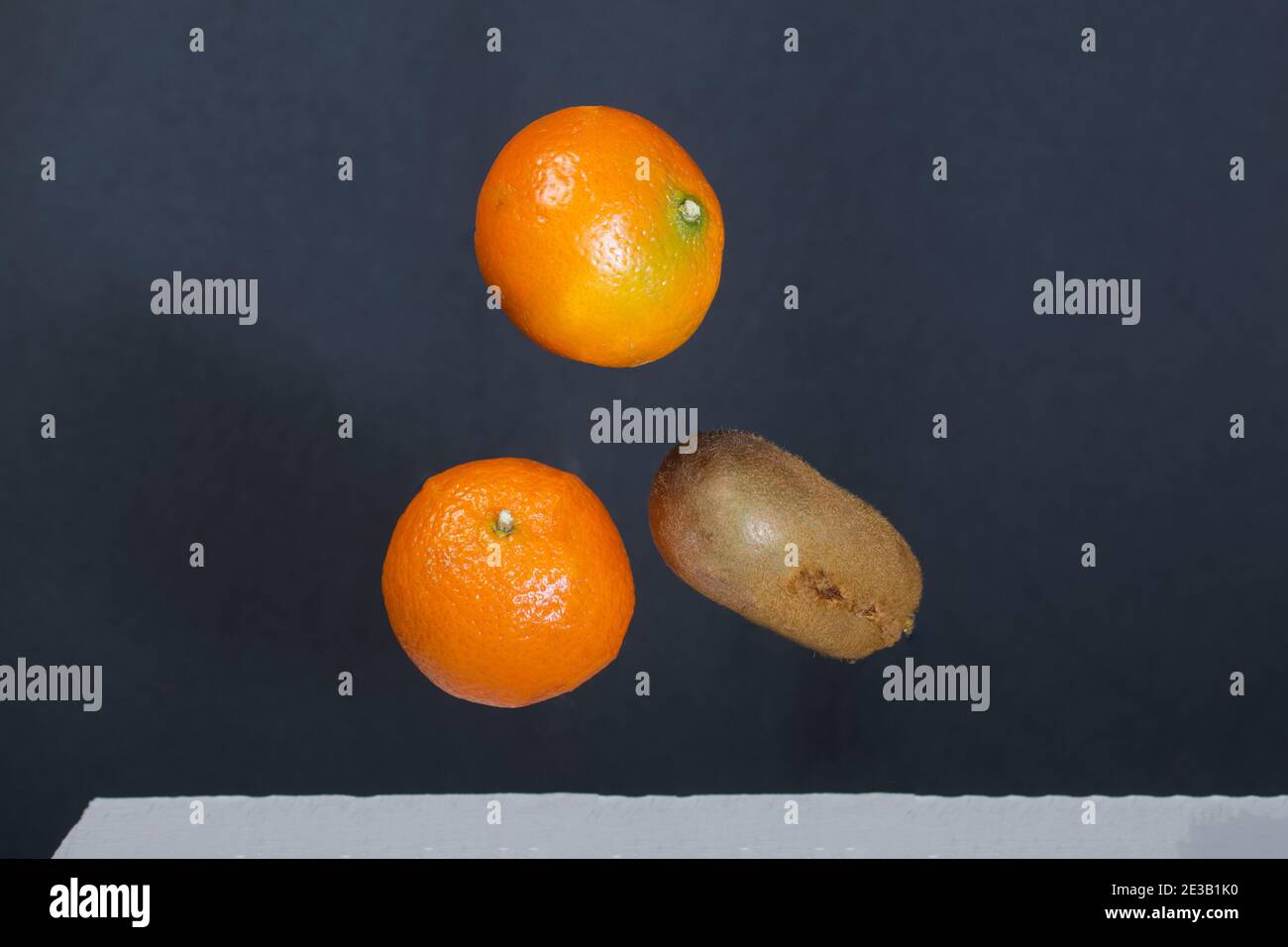 Tangerines and kiwis float above the table surface. Fruit levitation ...