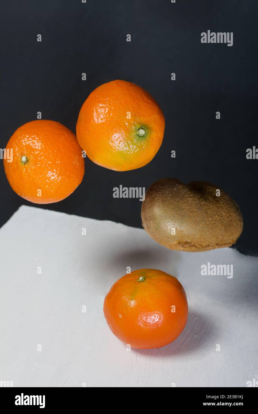 Tangerines and kiwis float above the table surface. Fruit levitation ...