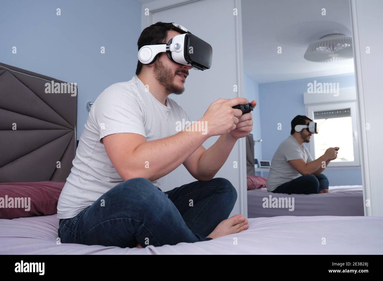 Young man playing video games with virtual reality headset and gamepad ...