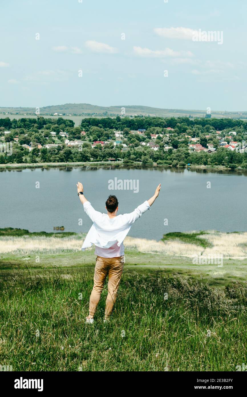 young smiling man standing on cliff catching wind. copy space. summer ...