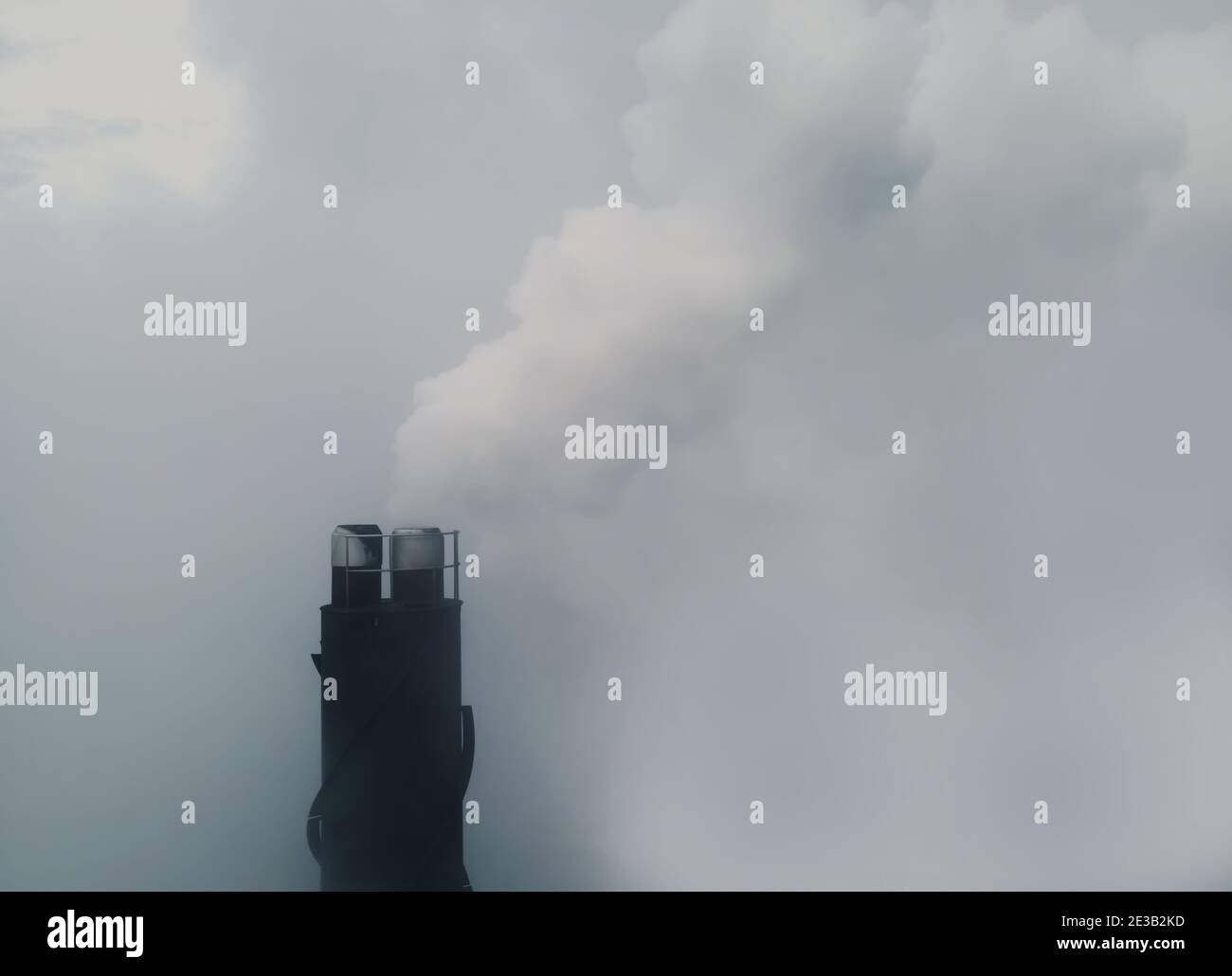 White smoke streaming out of a large industrial smoke stack at a ...