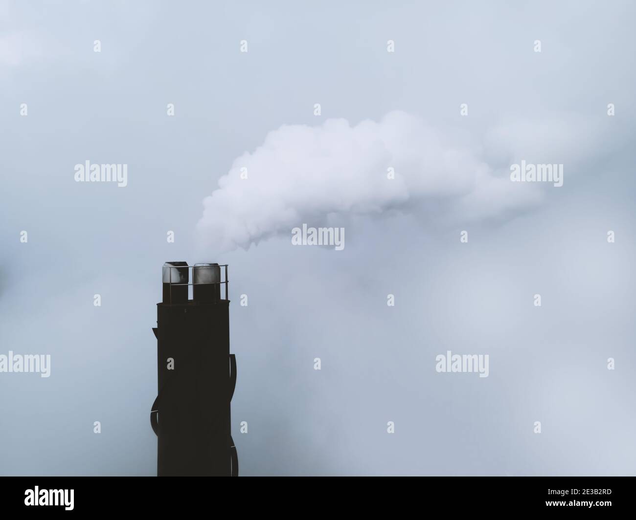 White smoke streaming out of a large industrial smoke stack at a ...