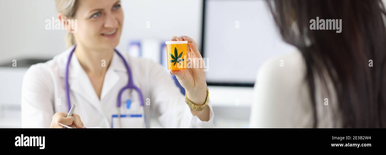 Doctor holding jar of marijuana pills in hands in front of patient in ...