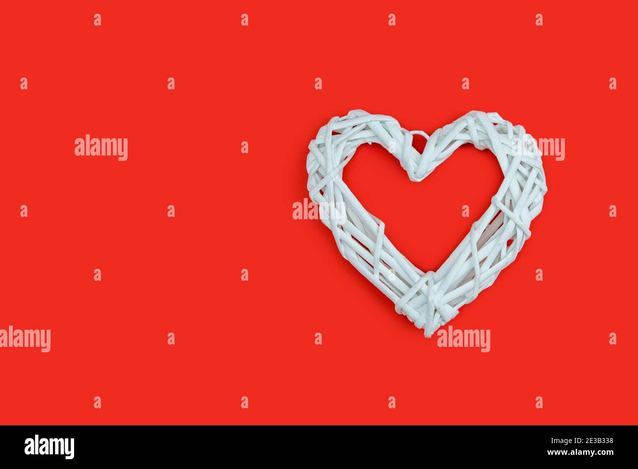White wicker heart symbol lies on the red background to Valentine's Day. Top view. Flat lay ...