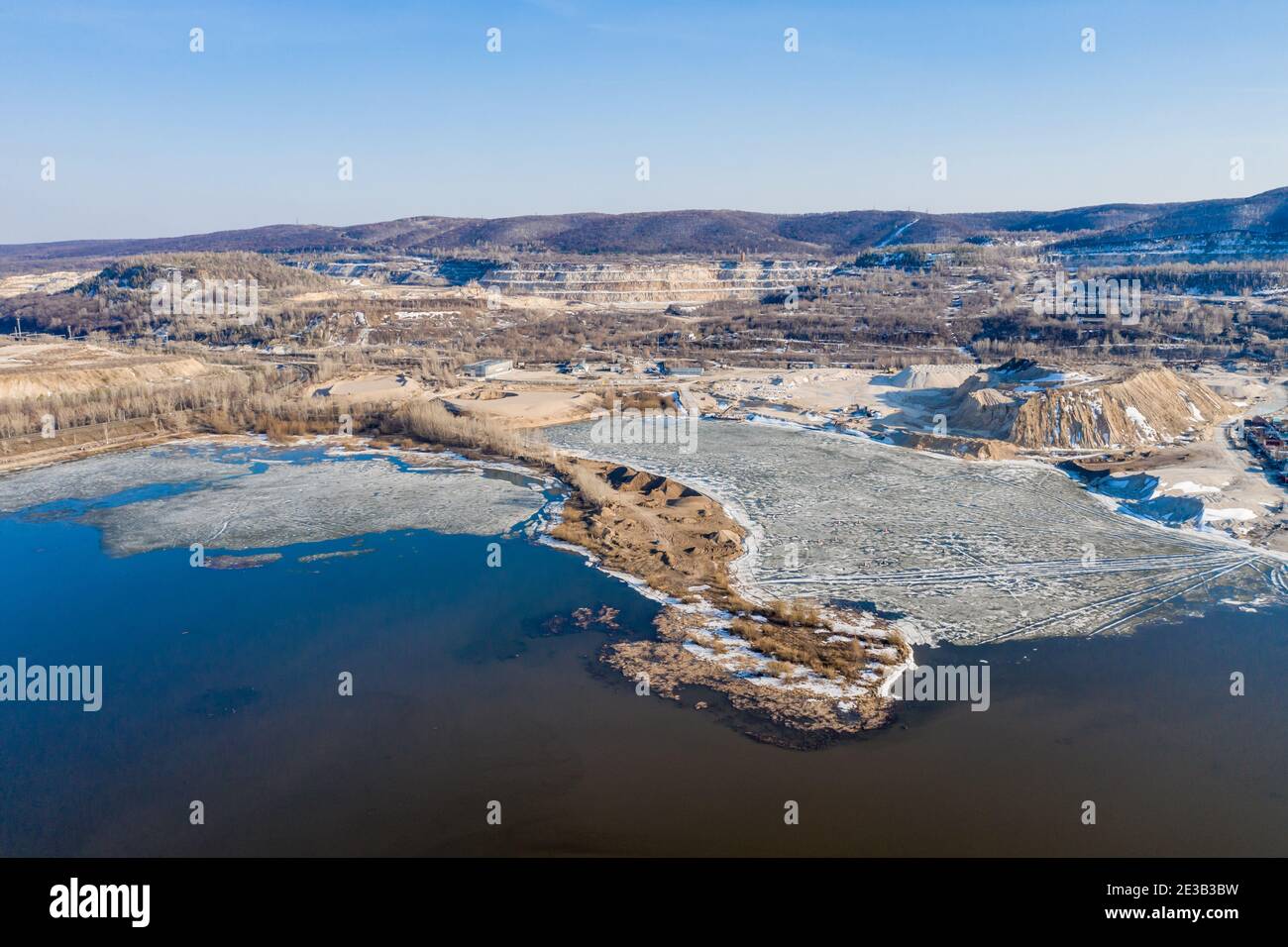 Old stone quarry opencast mine on river side in forest at winter Stock ...
