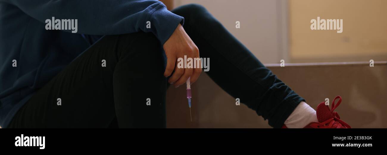 Addict sits with his head down and holds syringe in his hands Stock ...