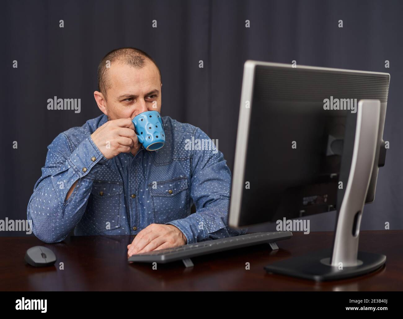 Businessman at his desk with his computer drinking a cup of cofee or ...