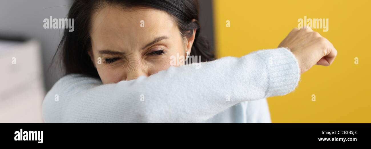 Young Woman sneezes into her elbow closeup Stock Photo - Alamy
