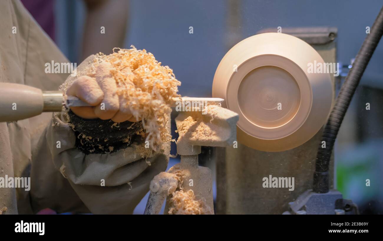 Carpenter using chisel for shaping piece of wood on lathe: close up ...