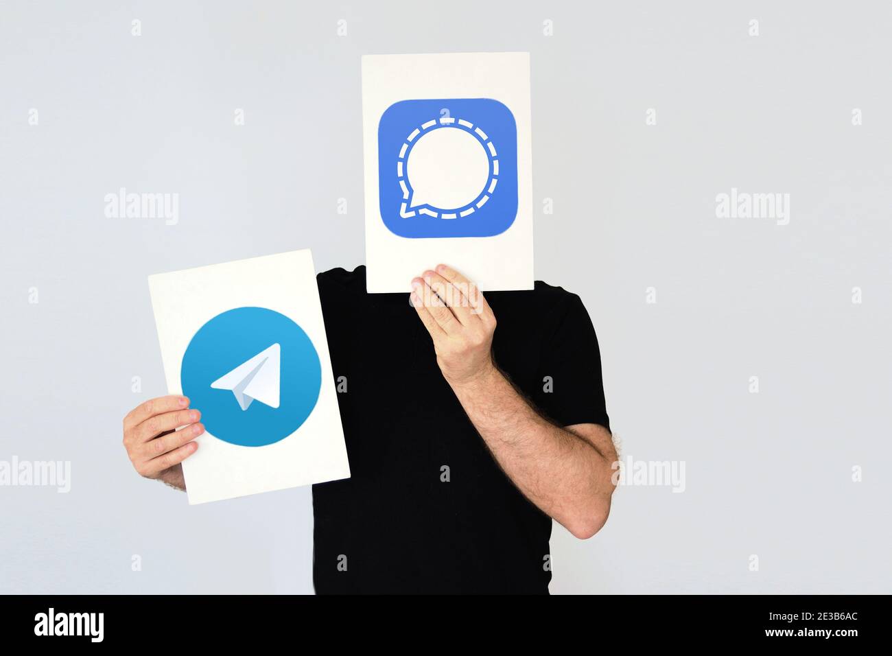 Man holding two cards with the Telegram and Signal logos on it. Empty ...