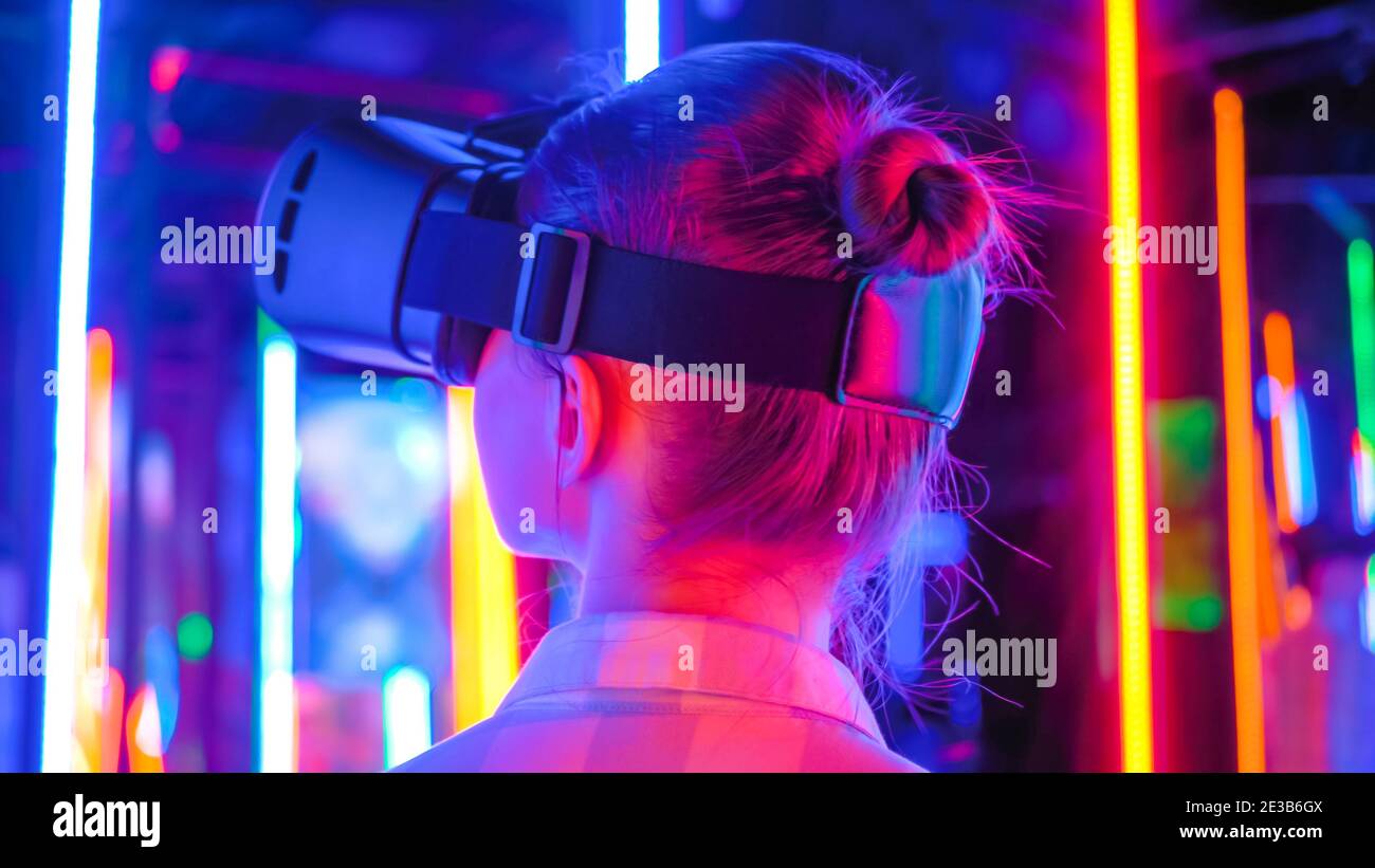 Back view: woman using virtual reality headset at interactive VR ...