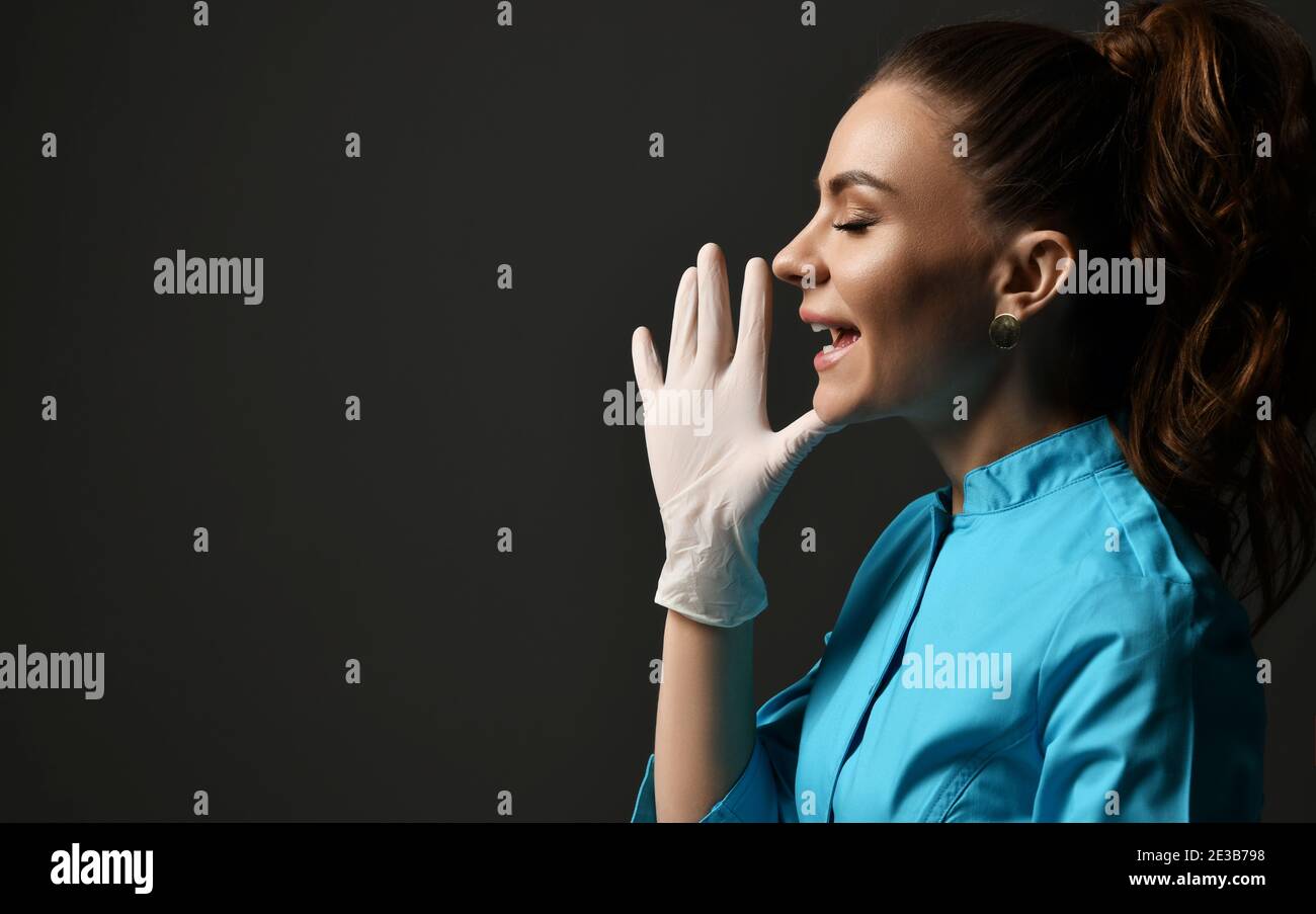 Talking or screaming young woman doctor in blue medical gown and latex ...
