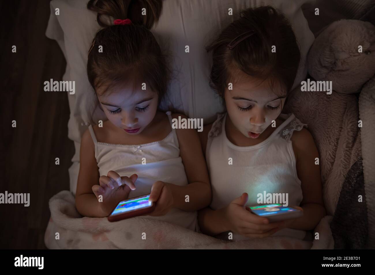 Little girls watching smartphone in bed, kids using phone and play game ...
