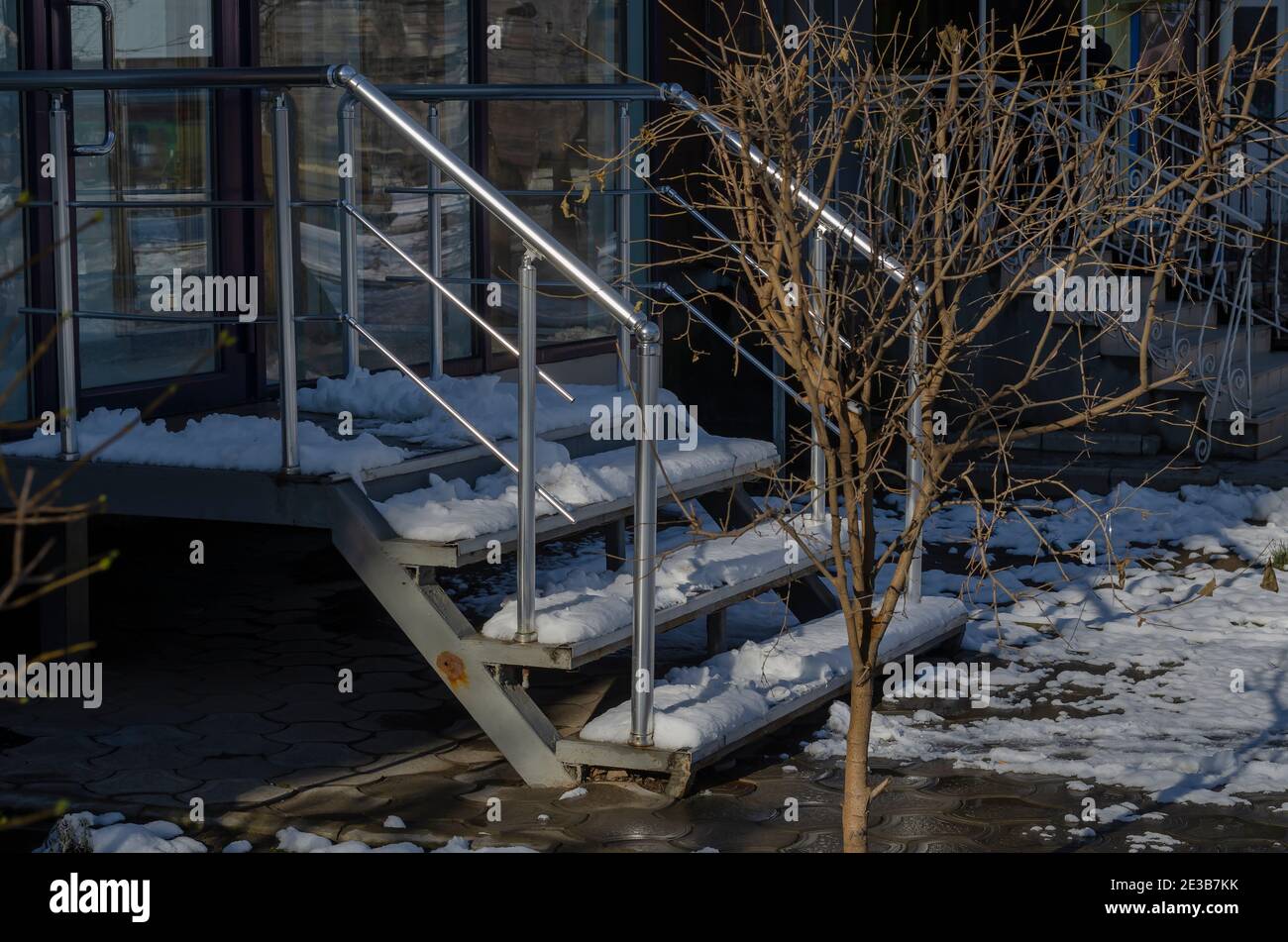 Stainless steel railings and steps in the snow. Exterior entrance to ...