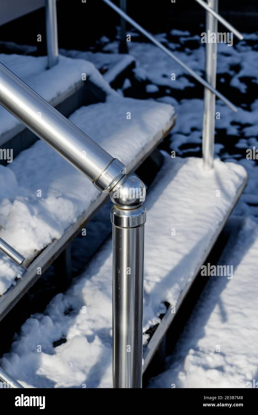 Stainless steel railings and steps in the snow. Exterior entrance to ...
