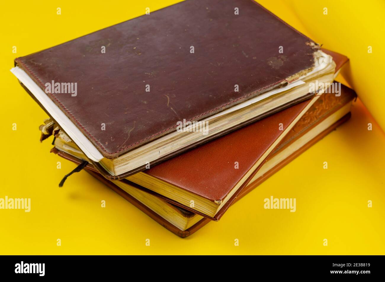 Stack of old diaries lying on yellow background. Diaries have worn ...