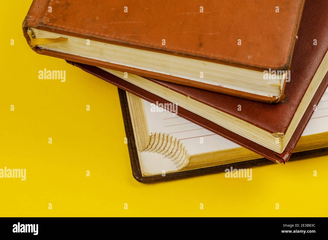 Stack of old diaries lying on yellow background. Diaries have worn ...