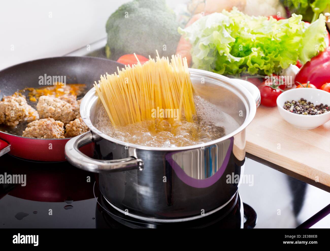 Cooking spaghetti in a pot with boiling water on a cooker on a kitchen ...