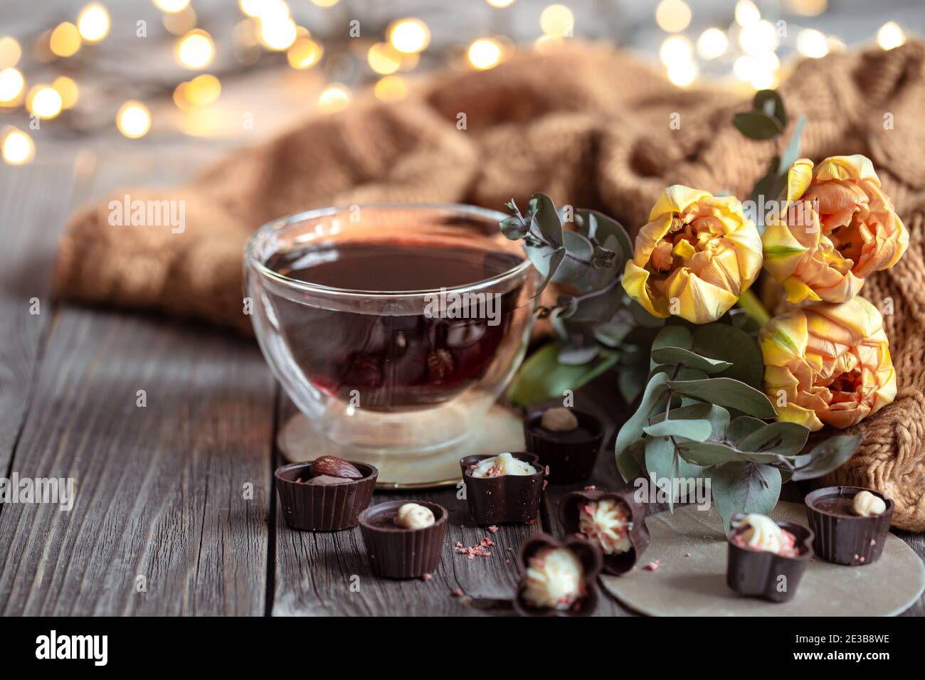 Festive still life with a drink in a cup, chocolates and flowers on a ...
