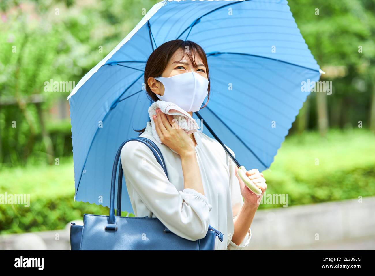 Young Japanese businesswoman wearing mask in the hot Summer downtown ...