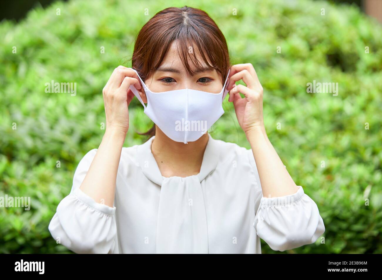 Young Japanese businesswoman wearing mask in the hot Summer downtown ...