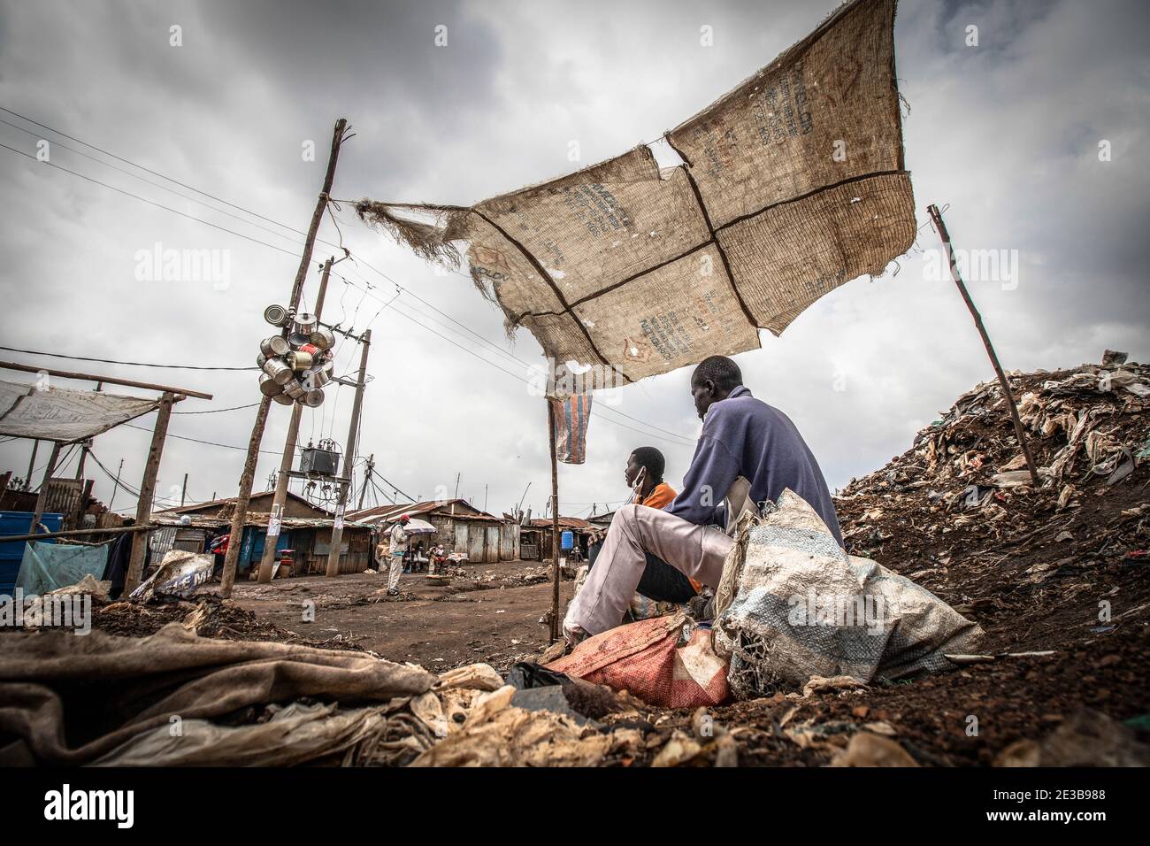 Two friends are seen chilling under a selfmade tent made with recycled ...