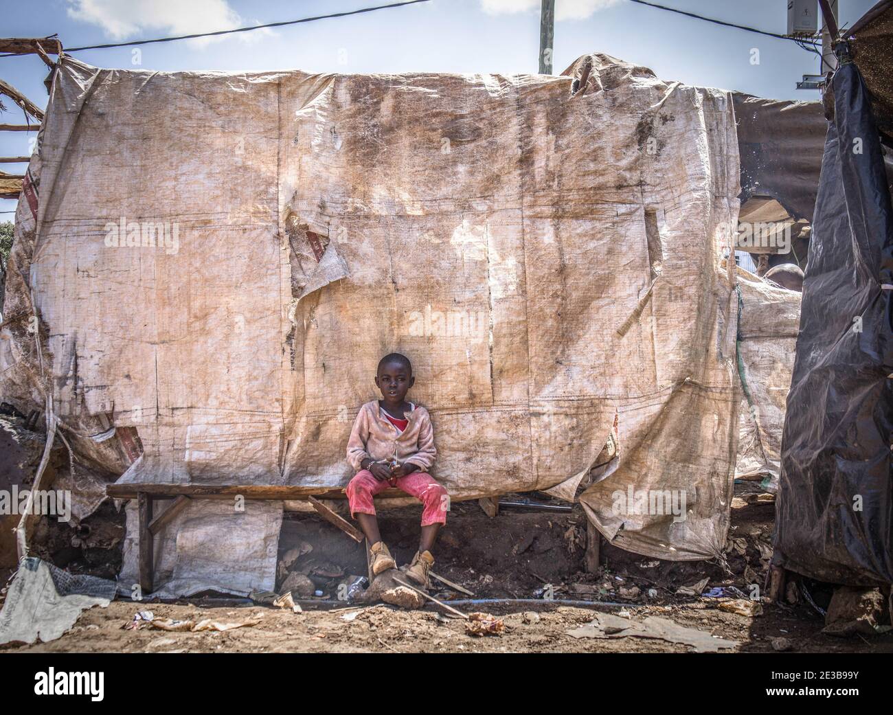 A young boy relaxing outside his small homemade house made with ...